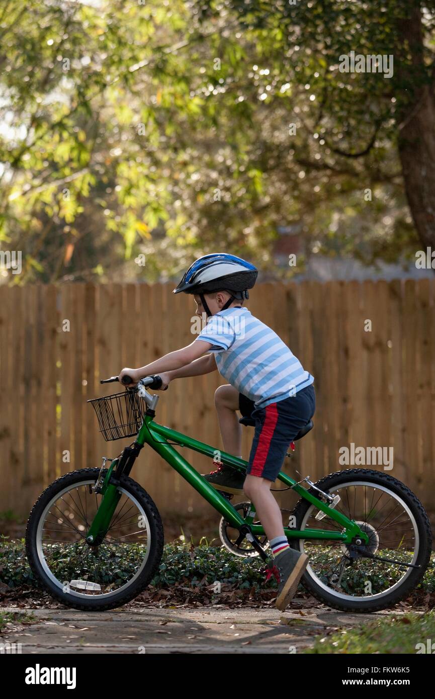 Boy riding bicycle past wooden fence Stock Photo - Alamy