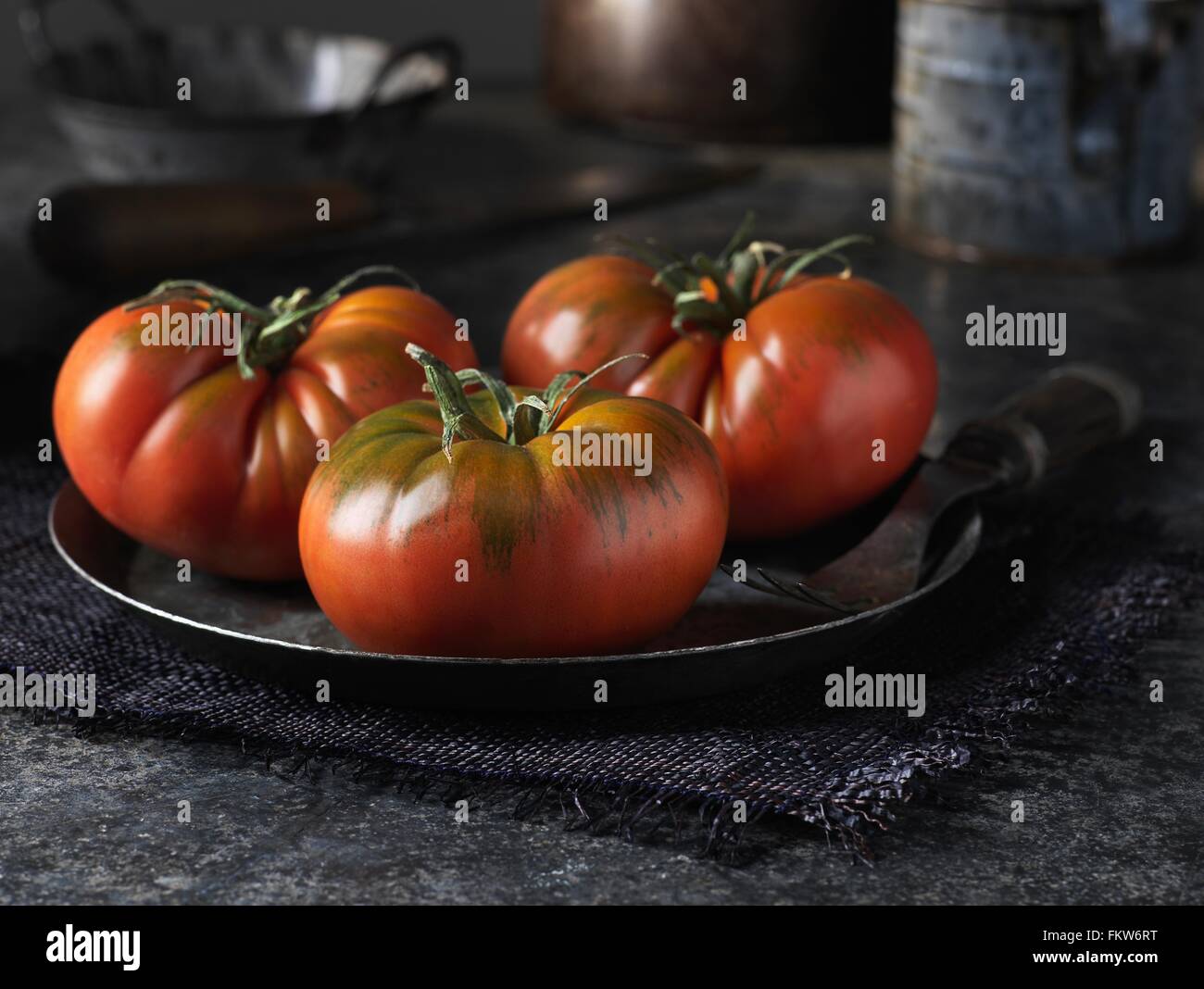 Red beef tomatoes on vintage metal plate Stock Photo - Alamy