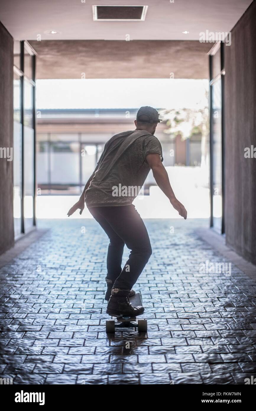 Rear view of young male skateboarder skateboarding in city Stock Photo ...