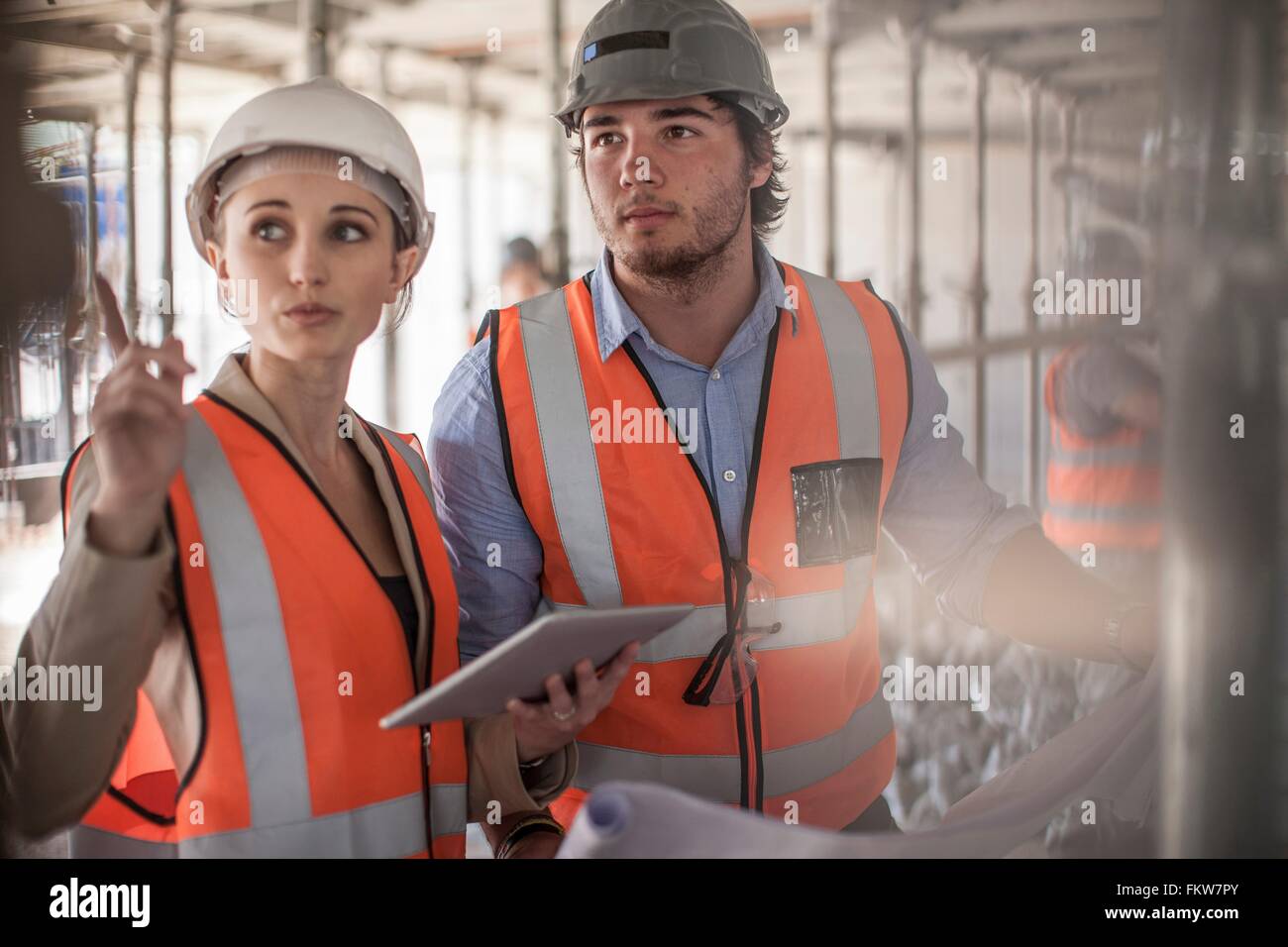 Female and male builders using digital tablet on construction site ...