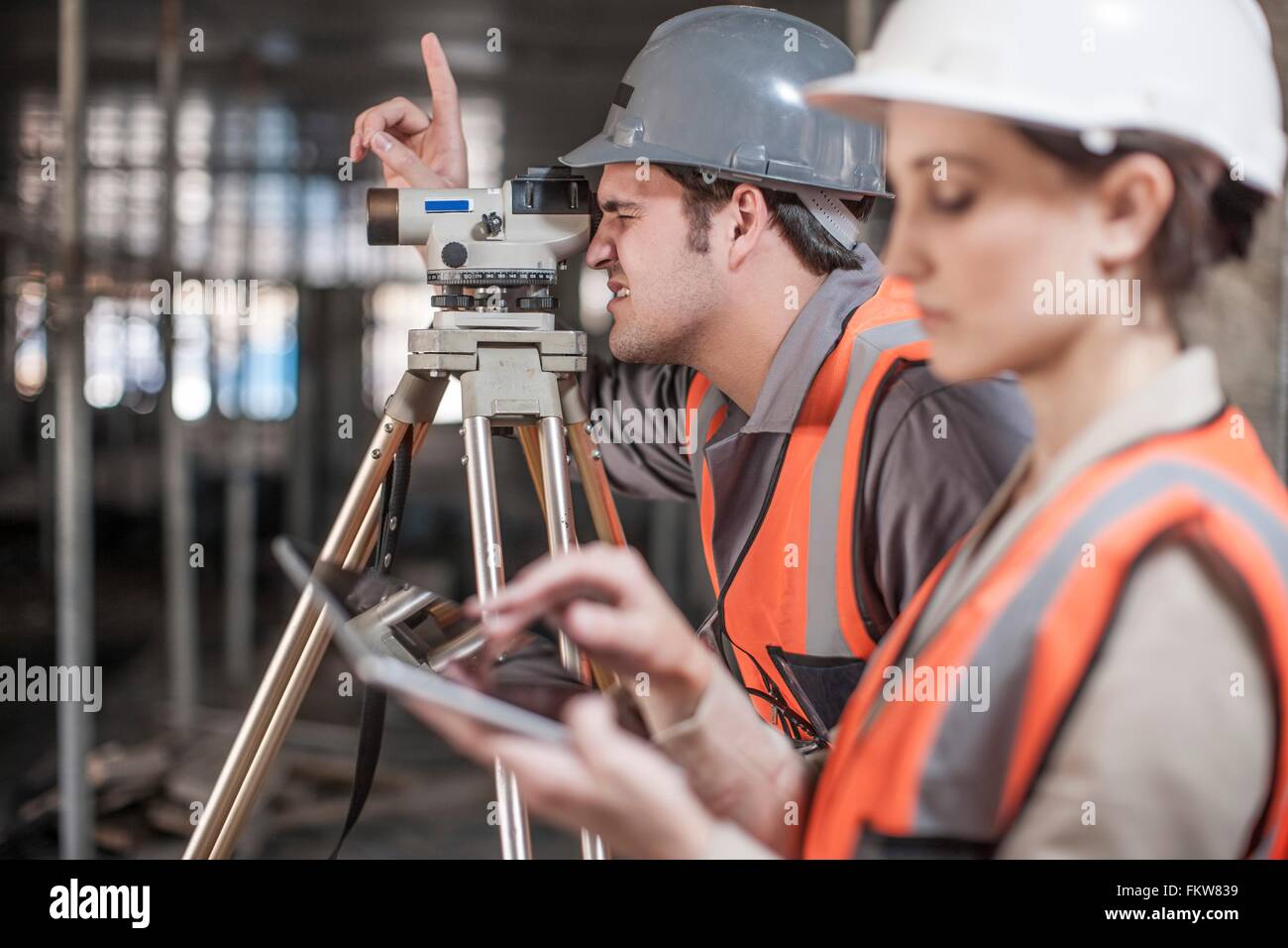 Female and male surveyor using digital tablet and theodolite on ...