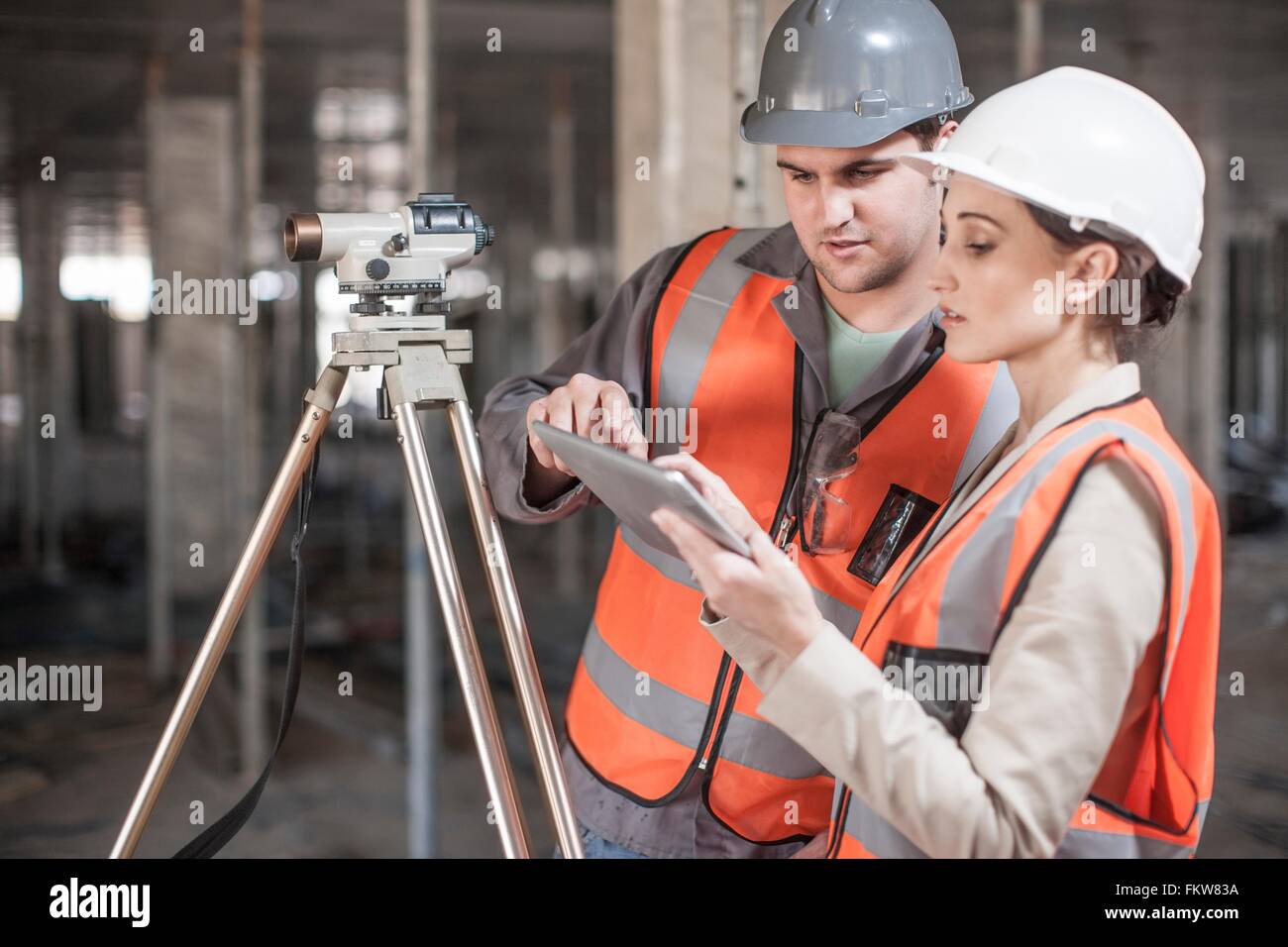 Female and male surveyor using digital tablet on construction site ...