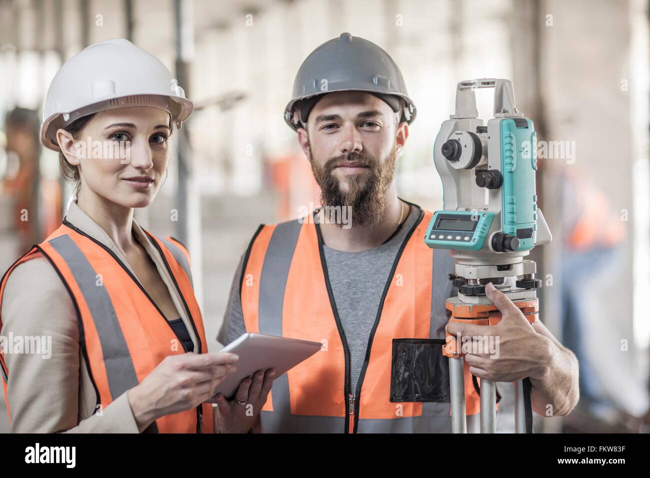 Portrait of young male and female surveyors on construction site Stock ...