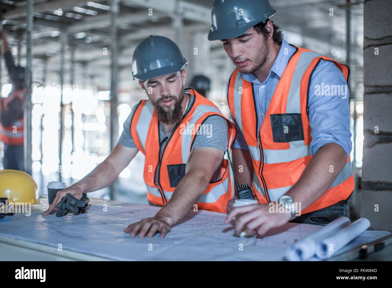Site foreman and builder looking at blueprint in construction site ...