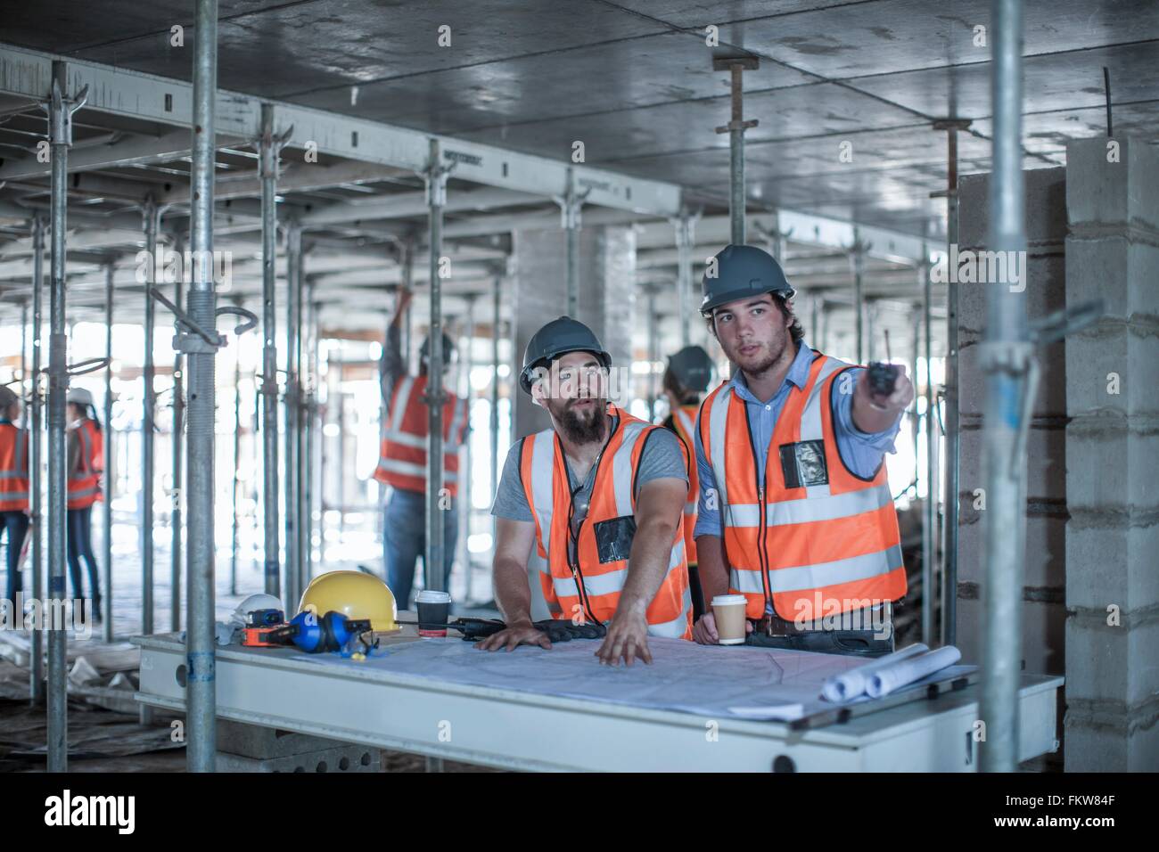 Site foreman and builder pointing from blueprint in construction site ...