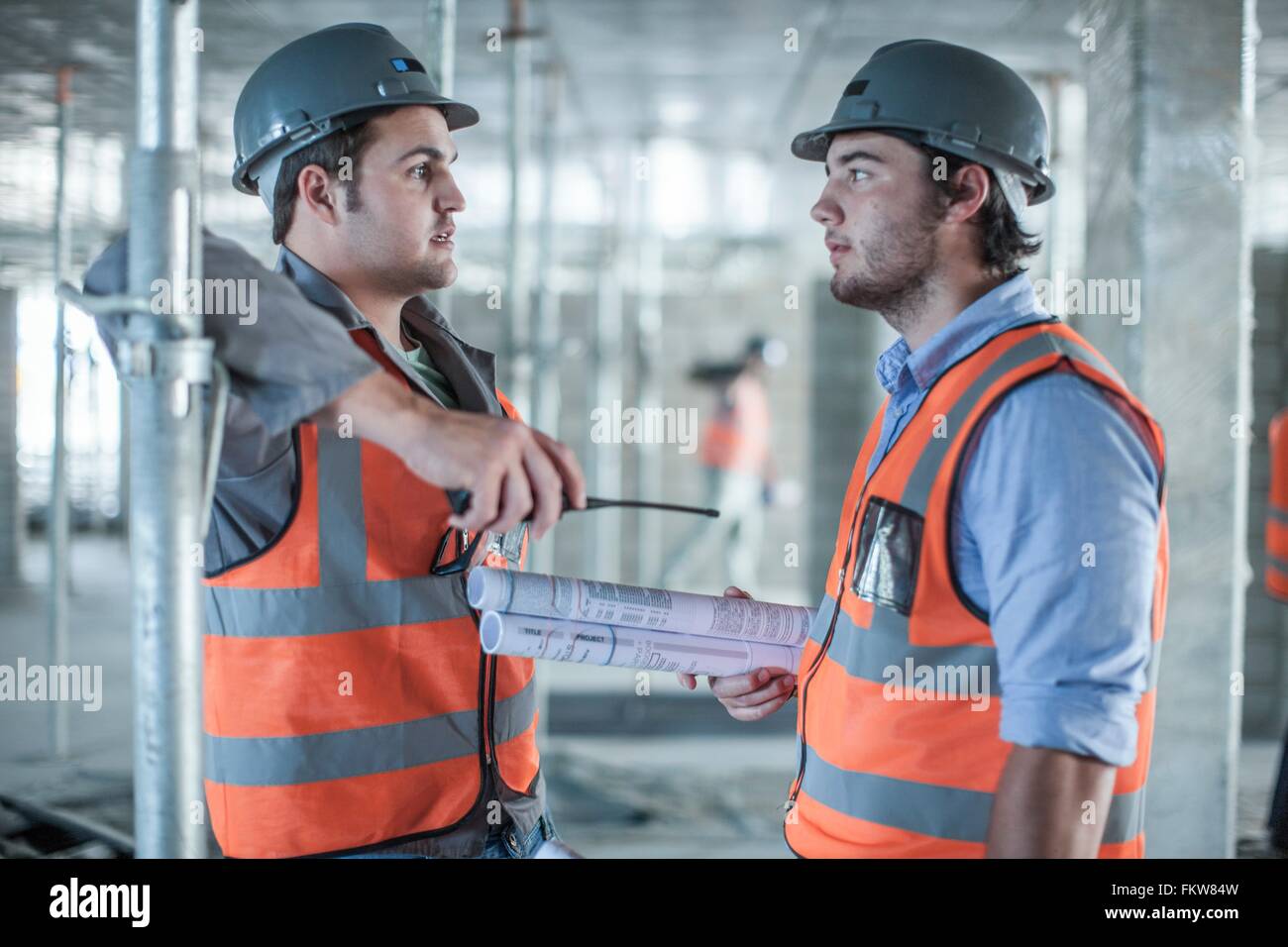 Site manager and builder discussing blueprint on construction site ...