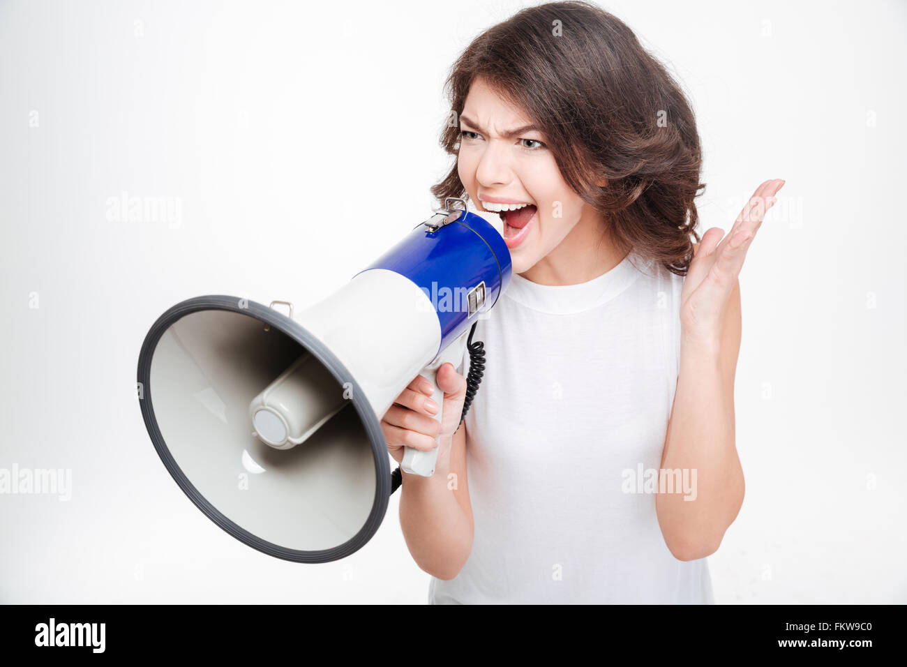 Young woman screaming into megaphone isolated on a white background ...