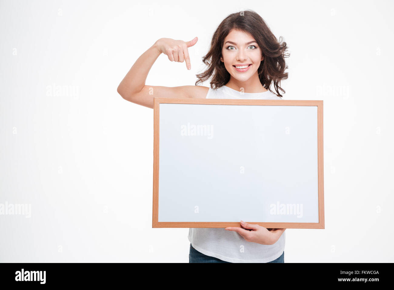 Portrait of a smiling woman pointing finger on blank board isolated on ...