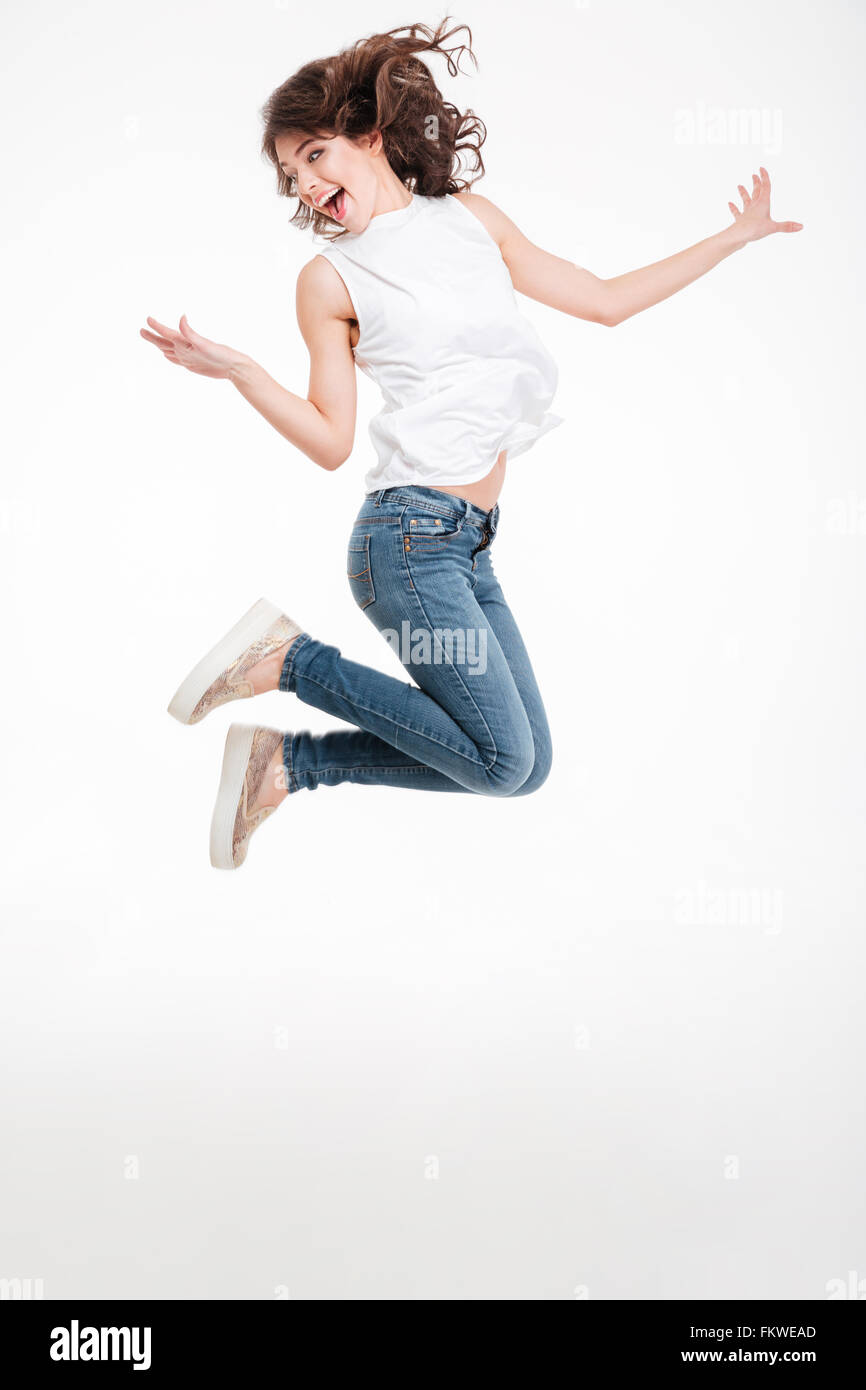 Full length portrait of a cheerful woman jumping isolated on a white ...