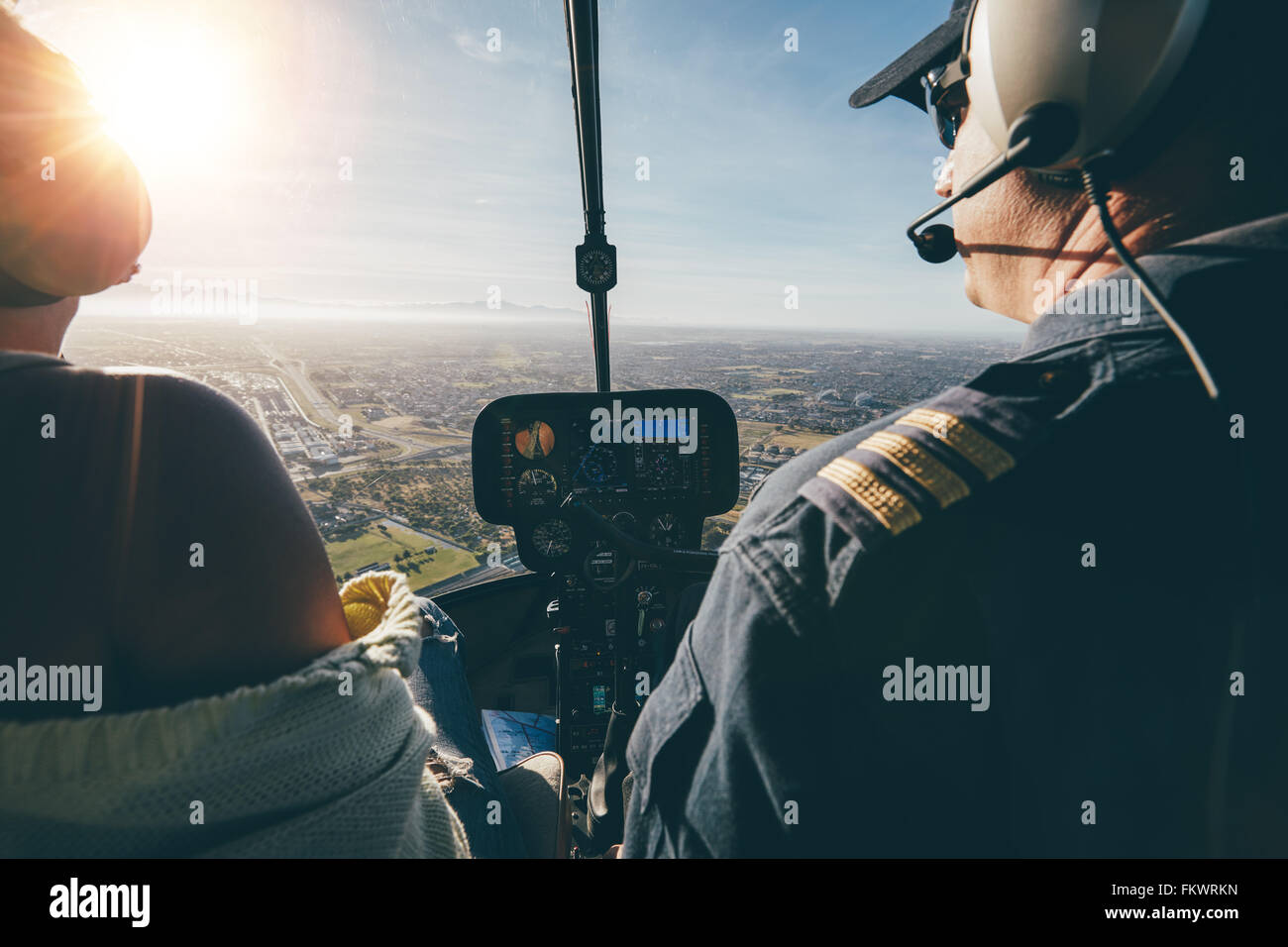 Rear view of two pilots flying a helicopter on sunny day. Close up shot ...