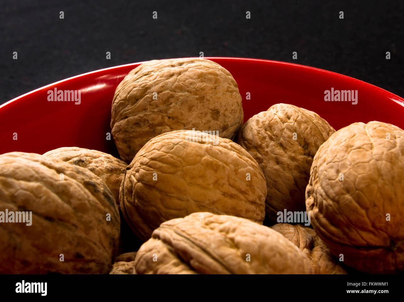 walnuts in red plate on black background Stock Photo - Alamy