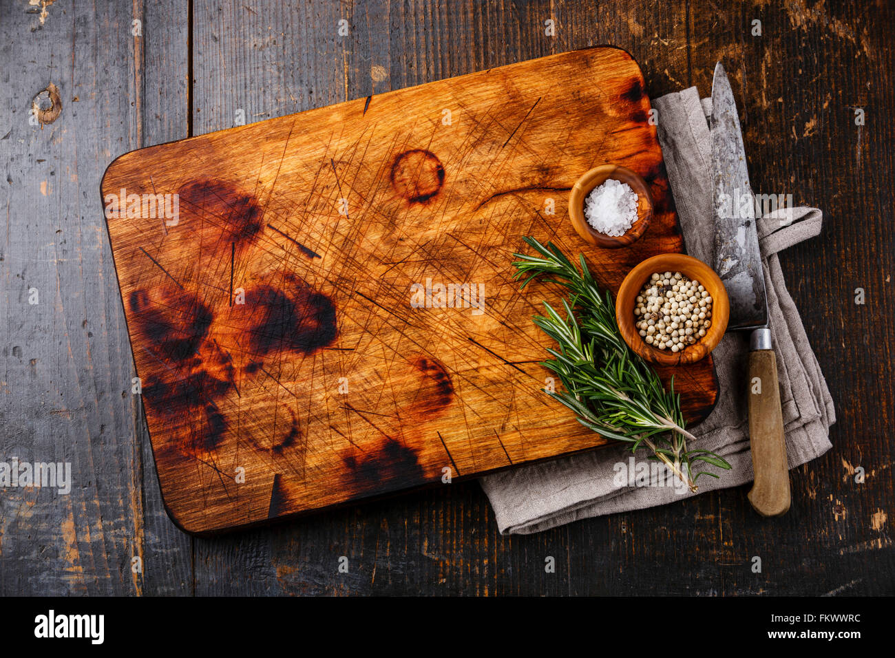 Chopping cutting board, salt, pepper and rosemary with kitchen knife on ...