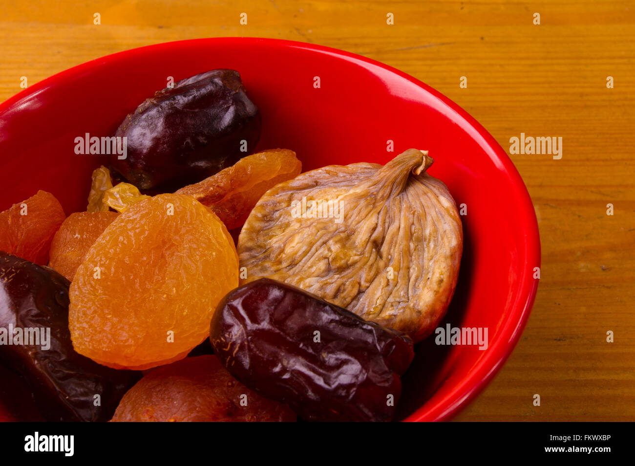 various dried fruits in red plate on wooden background Stock Photo - Alamy