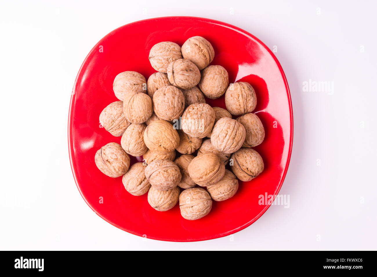 walnuts in red plate on white background Stock Photo - Alamy