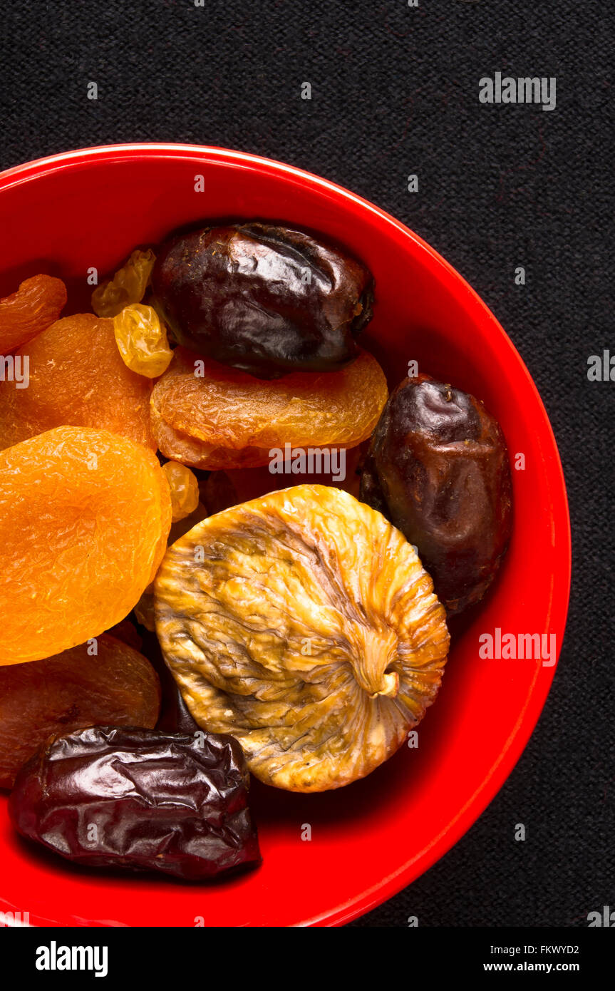 various dried fruits in red plate on the black background Stock Photo ...