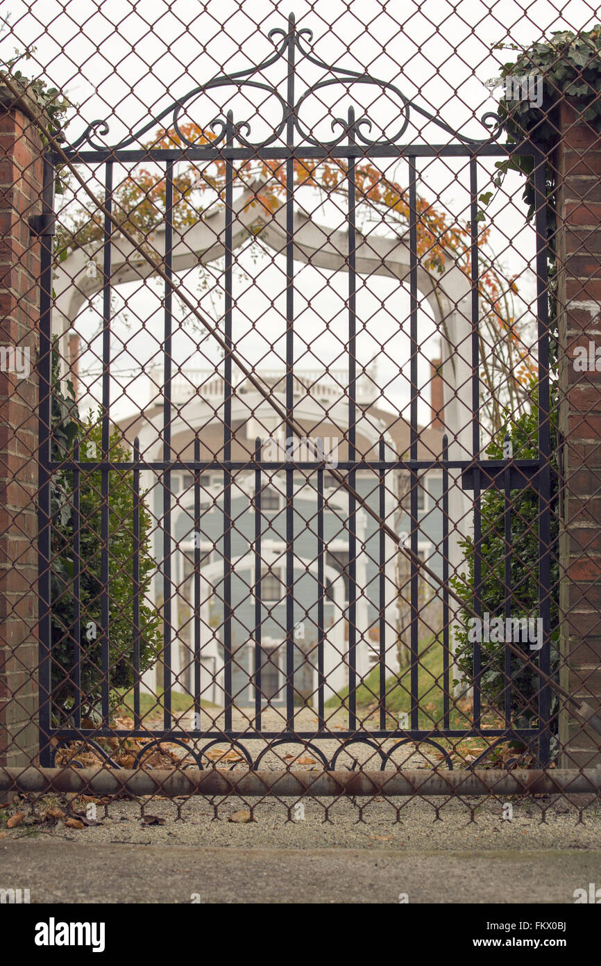Closed gate to a path leading through a garden to an old mansion Stock ...