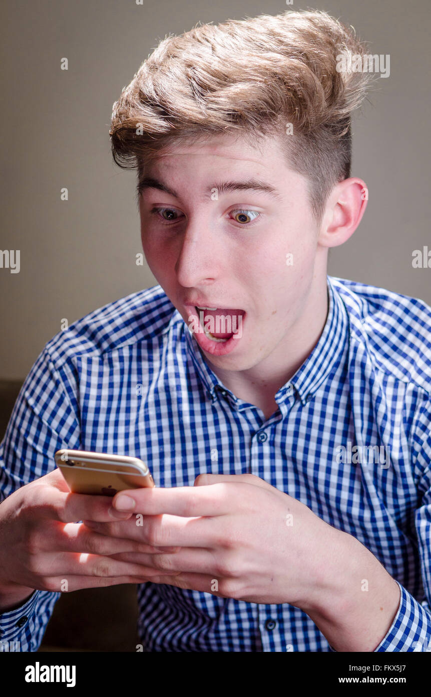 Young Man Using Smart Phone and Laughing Stock Photo - Alamy
