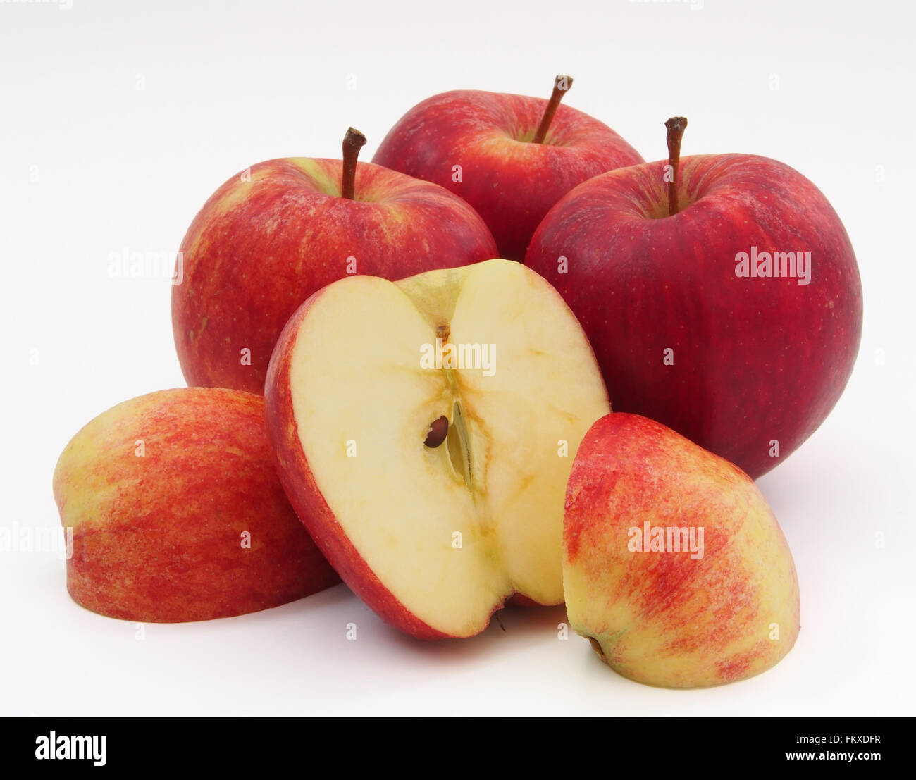 Four red Gala apples with one sliced in half and quarters showing the ...