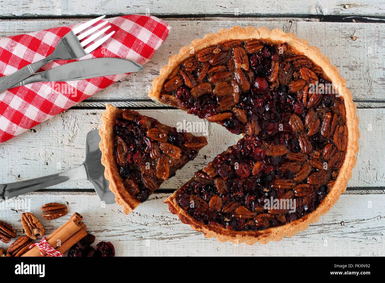 Pecan and cranberry autumn pie, overhead table scene on white wood with ...