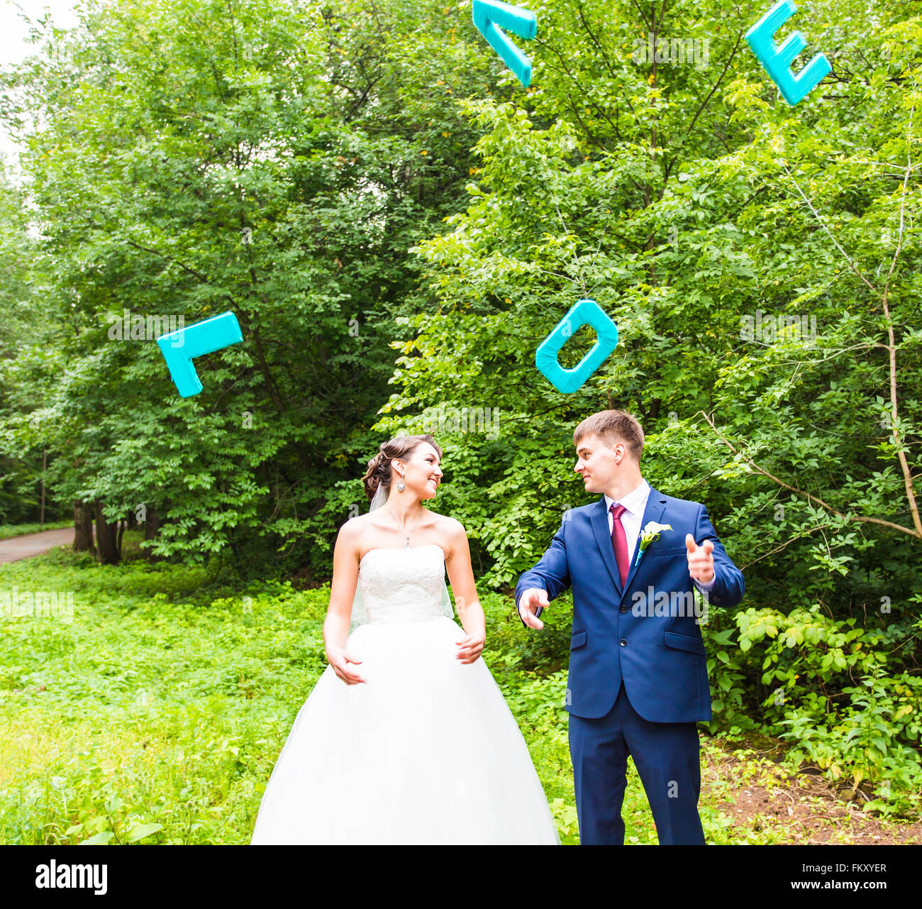 Happy bride and groom holding LOVE letters Stock Photo - Alamy