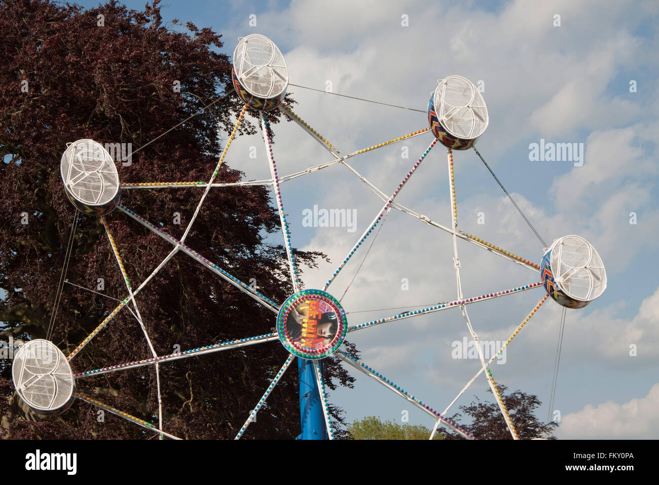 Funfair wheel ride against trees and sky Stock Photo - Alamy