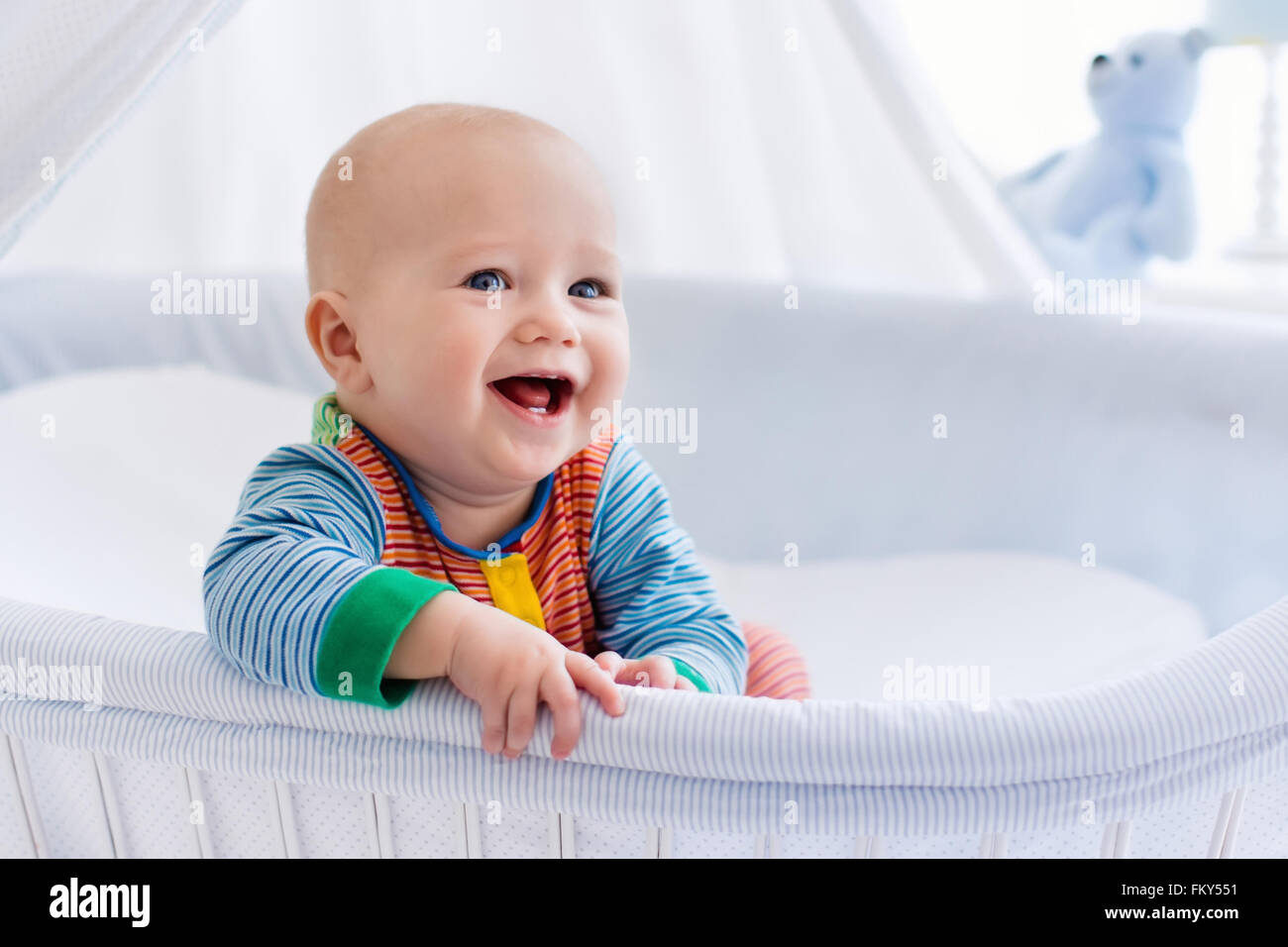 Funny baby in white crib with canopy. Nursery interior and bedding for ...