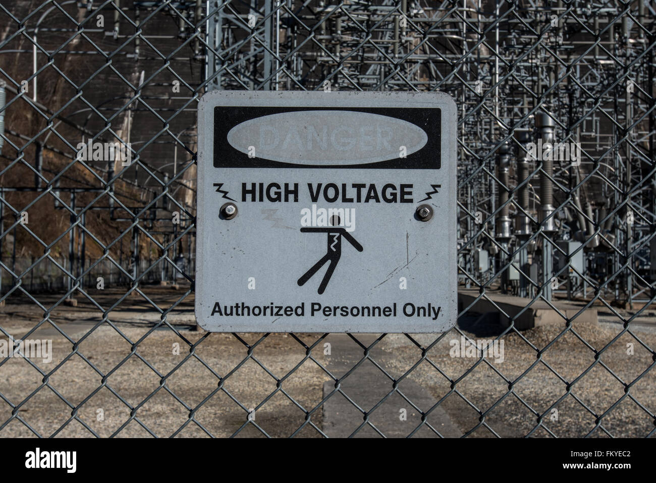 Faded high voltage danger sign on chainlink surrounding a power plant ...