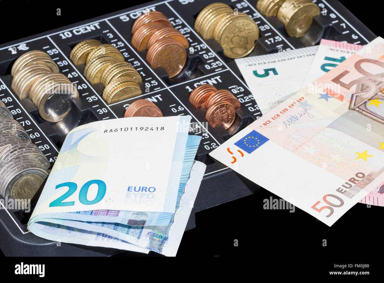 forefront of a euro coins organizer with coins and some euro bills ...