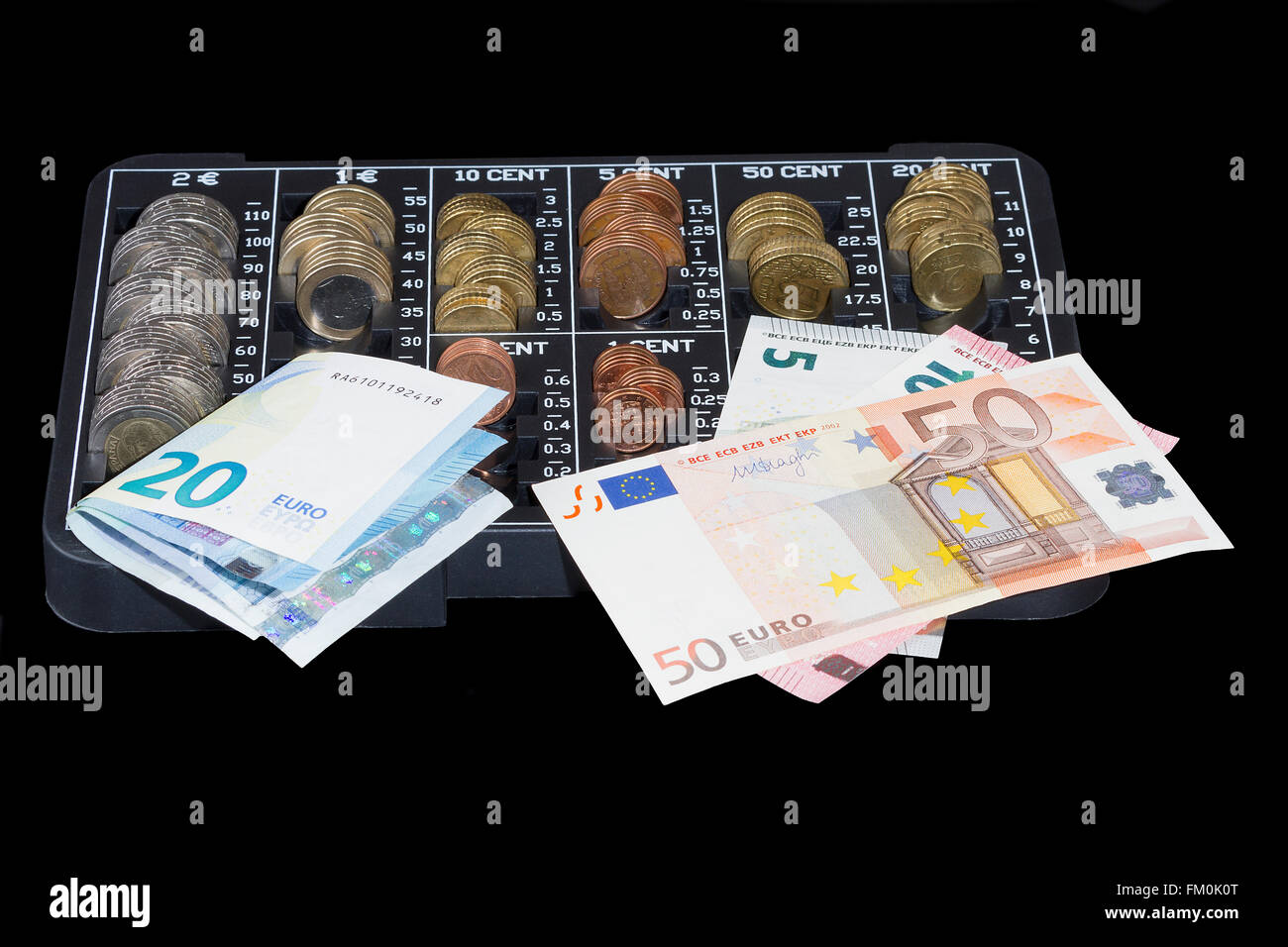 forefront of a euro coins organizer with coins and some euro bills on ...