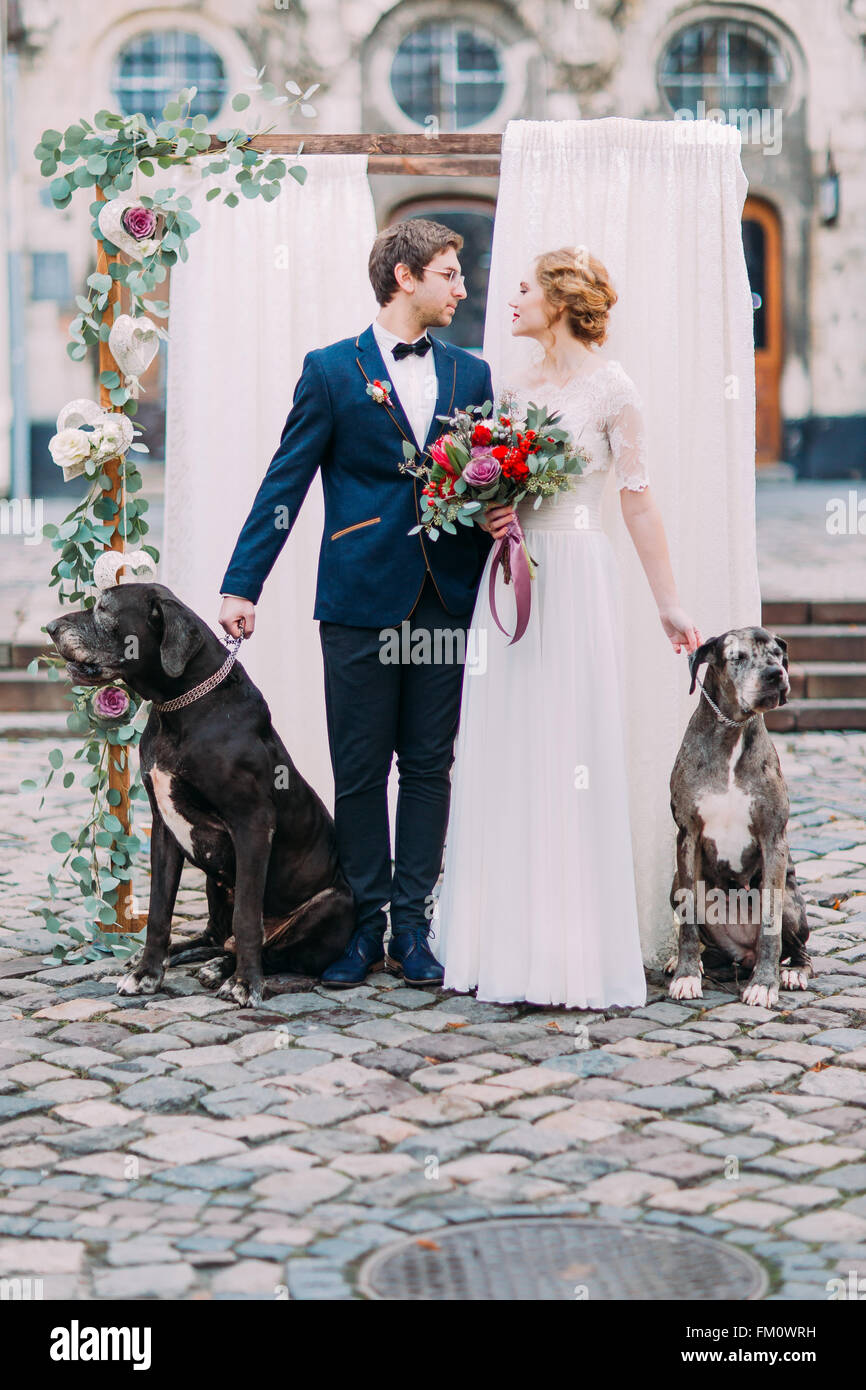 Happy beautiful bride and groom lovingly look at each other holding a ...