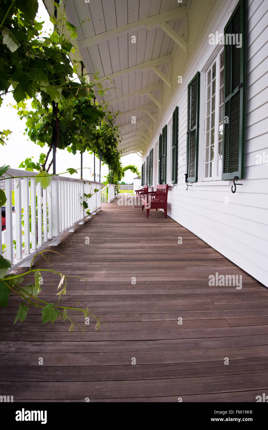 Maroon wooden bench on the covered wooden attic of a large white house ...