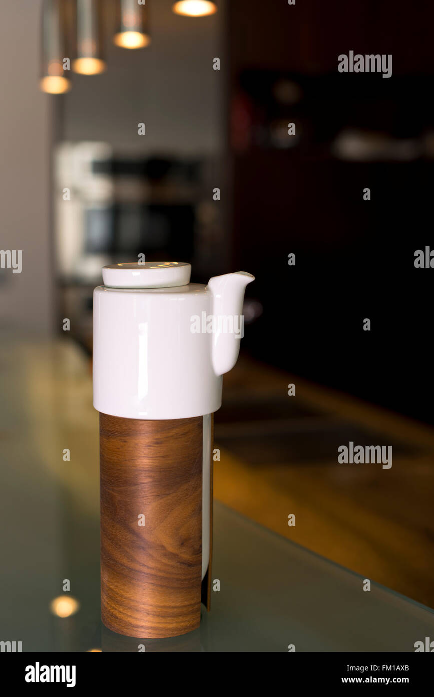 White modern porcelain coffee pot with wood support on blurred ...