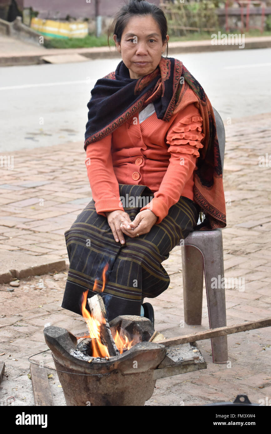 Vendor making a fire during intense cold front in Luang Prabang Laos ...