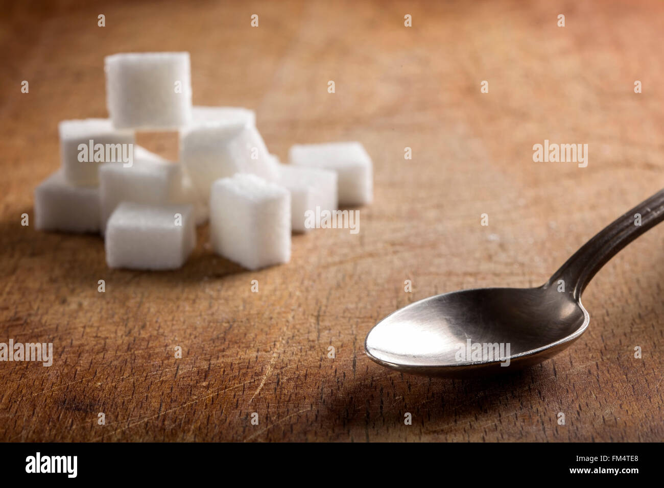 Empty spoon and sugar cubes in background over wood Stock Photo - Alamy