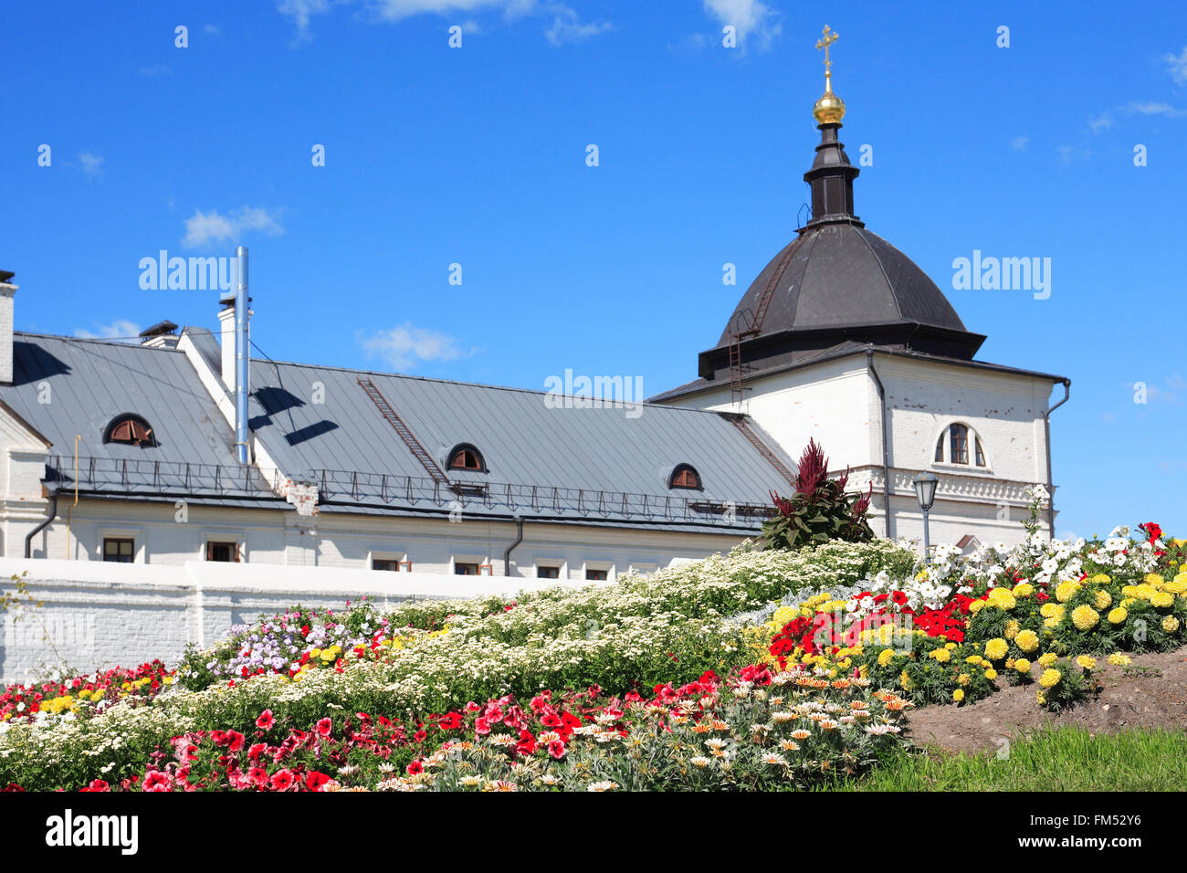 Nice white old Russian Christian monastery and flower-bed against blue ...