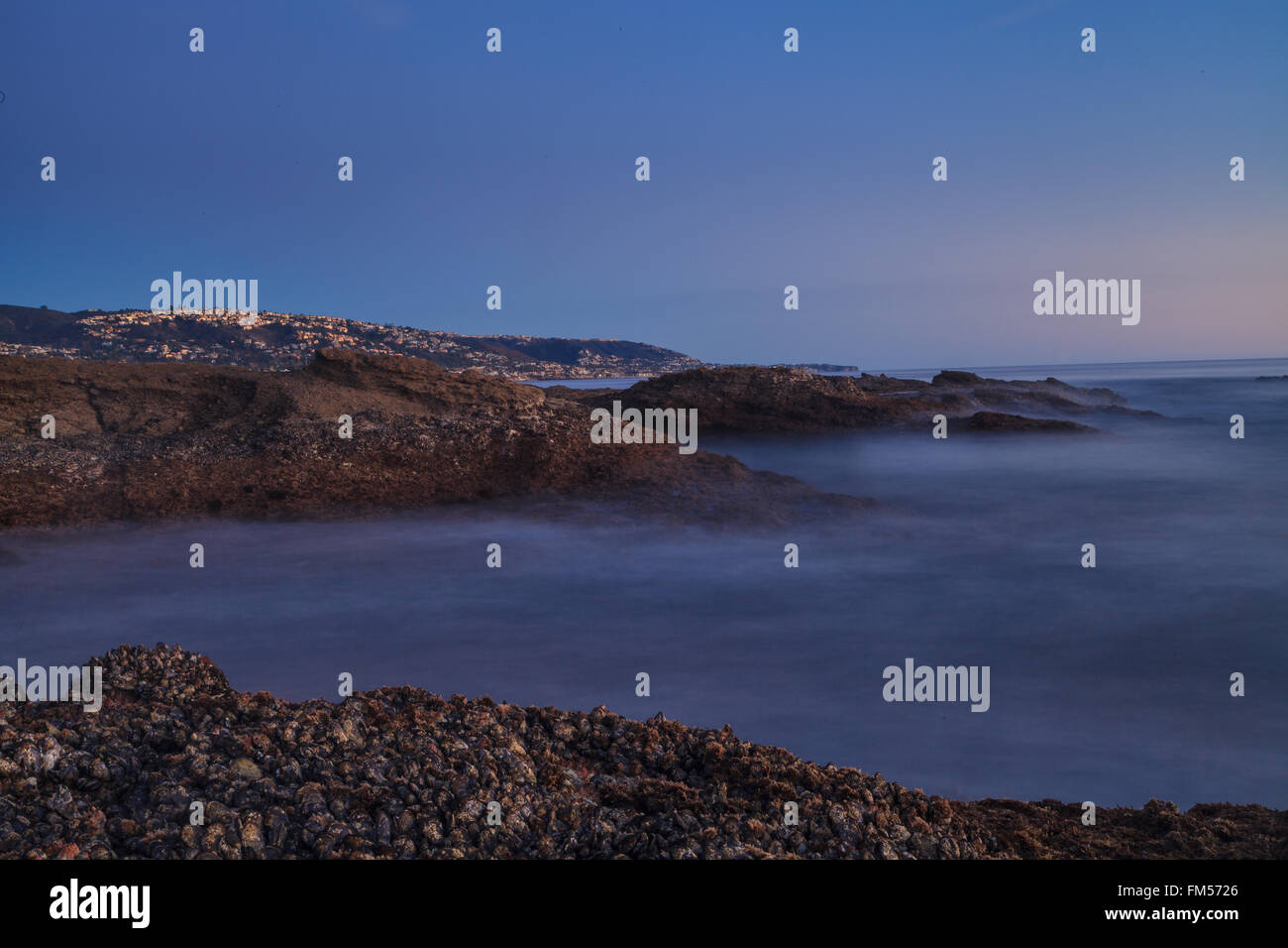 Long exposure of sunset over rocks, giving a mist like effect over ...