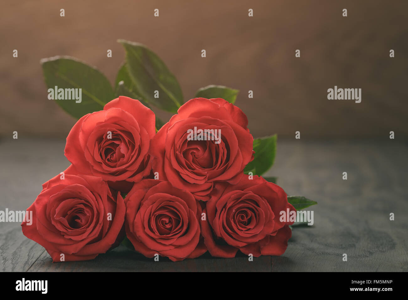 five red roses on wooden table Stock Photo - Alamy