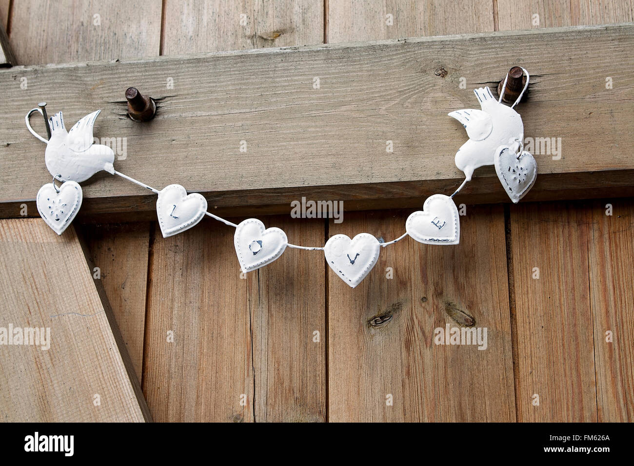 Decorative doves holding string of love hearts on wooden door Stock ...