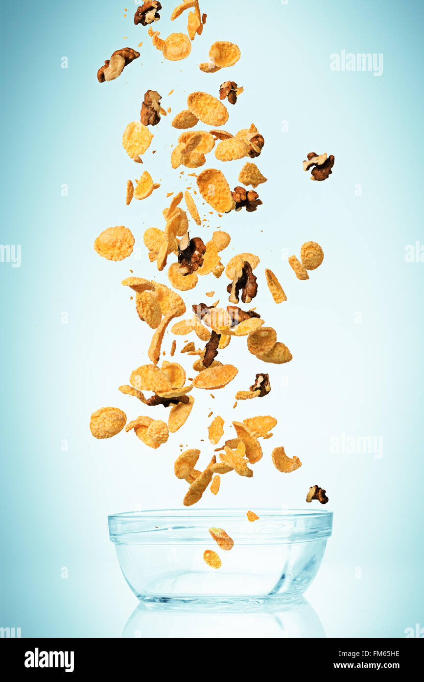 The cornflakes falling with walnuts into an empty glass bowl. Concept ...