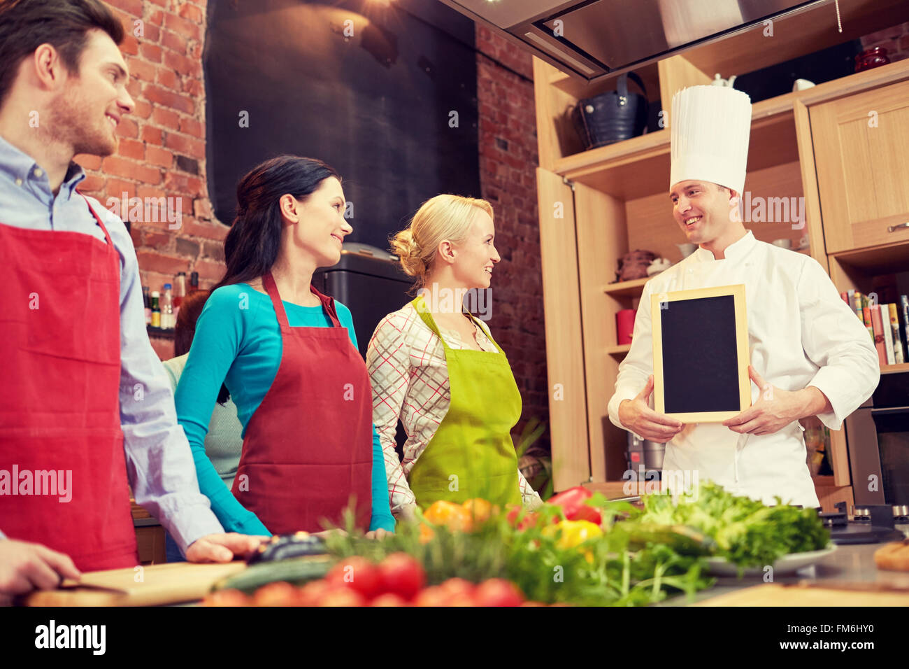happy friends and chef cook with menu in kitchen Stock Photo - Alamy