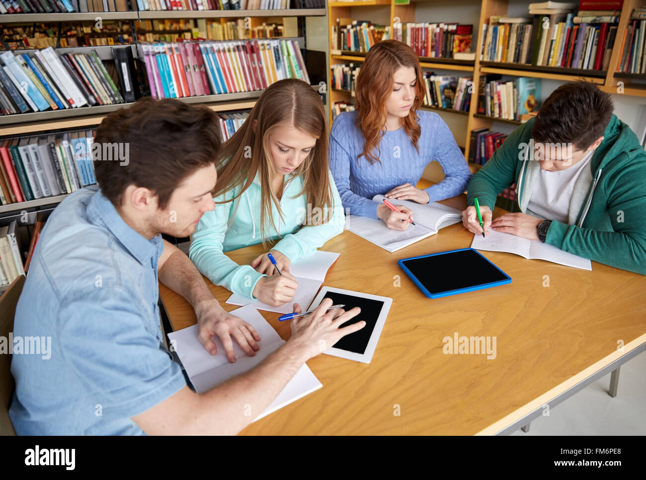 students writing to notebooks in library Stock Photo - Alamy