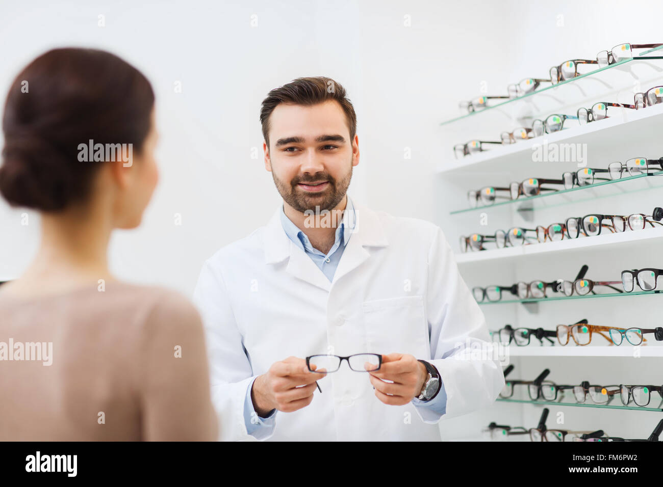 woman and optician showing glasses at optics store Stock Photo - Alamy