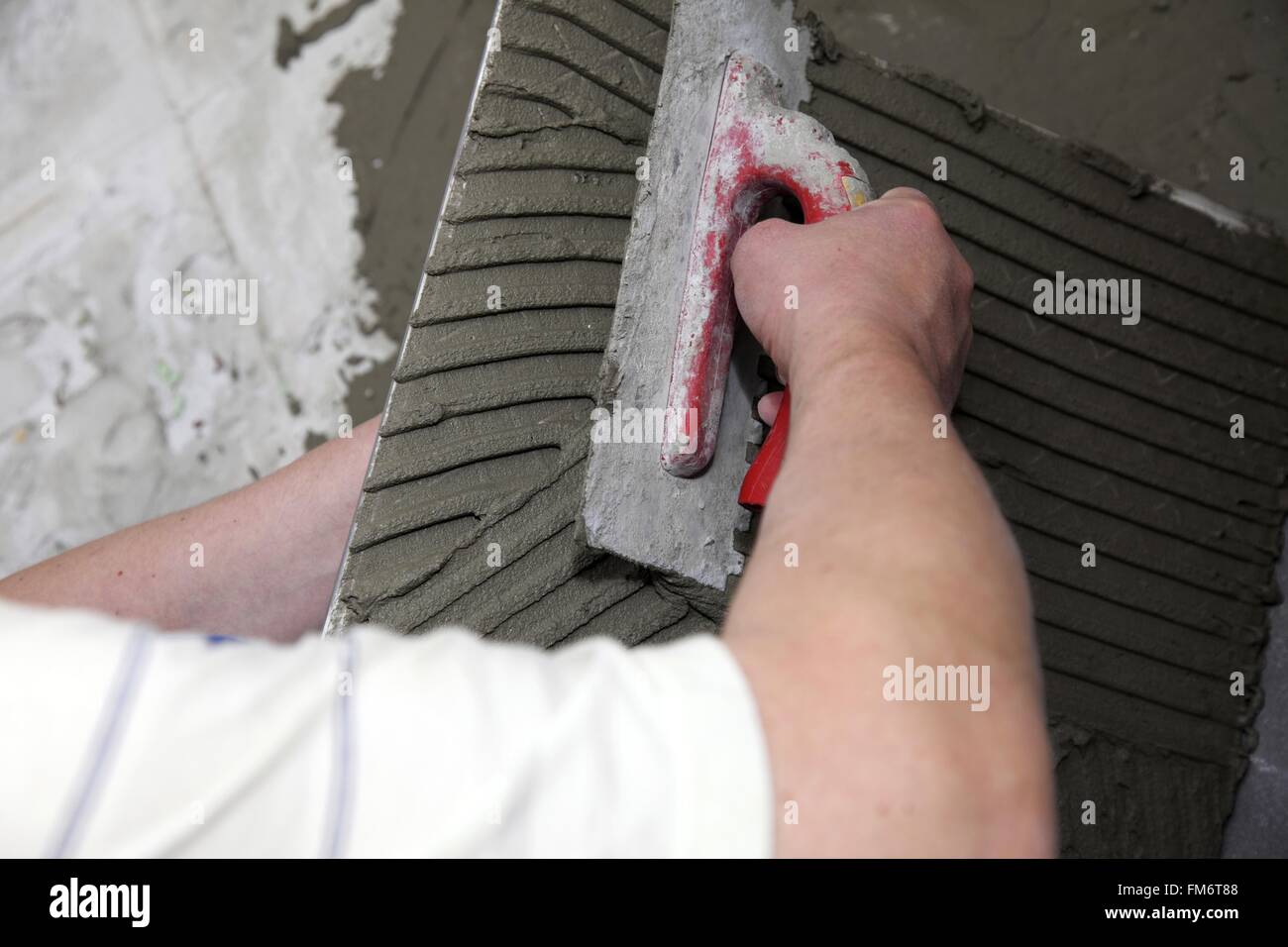 a tiler at work. bonding of floor tile with tile adhesive and filler ...
