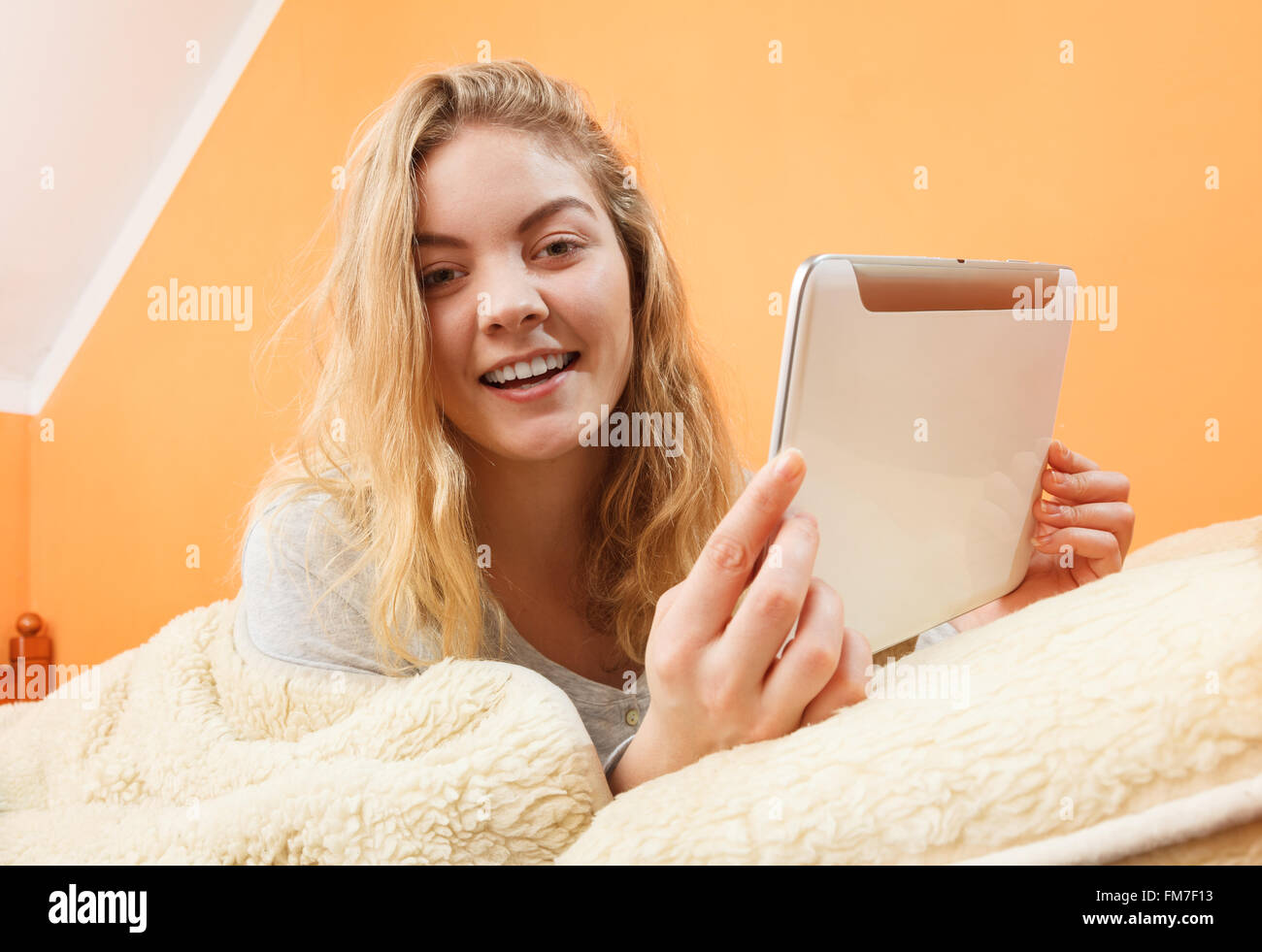Lazy young woman using computer tablet browsing internet. Girl laying ...