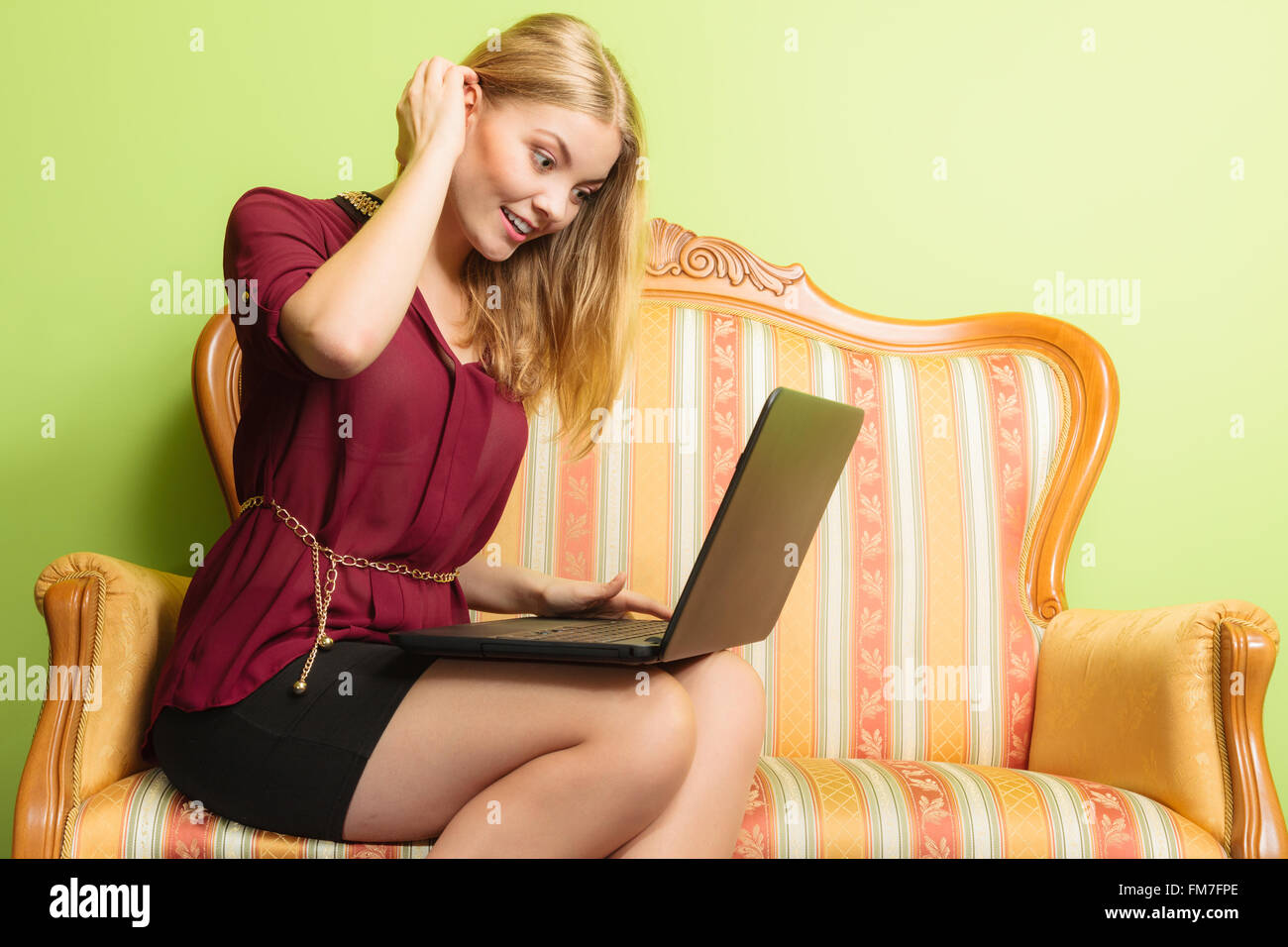 Young fashionable woman girl sitting on vintage retro sofa couch using ...