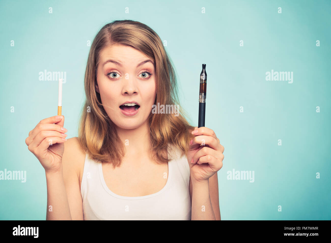 Surprised pretty girl smoking normal and electronic cigarette. Addicted ...