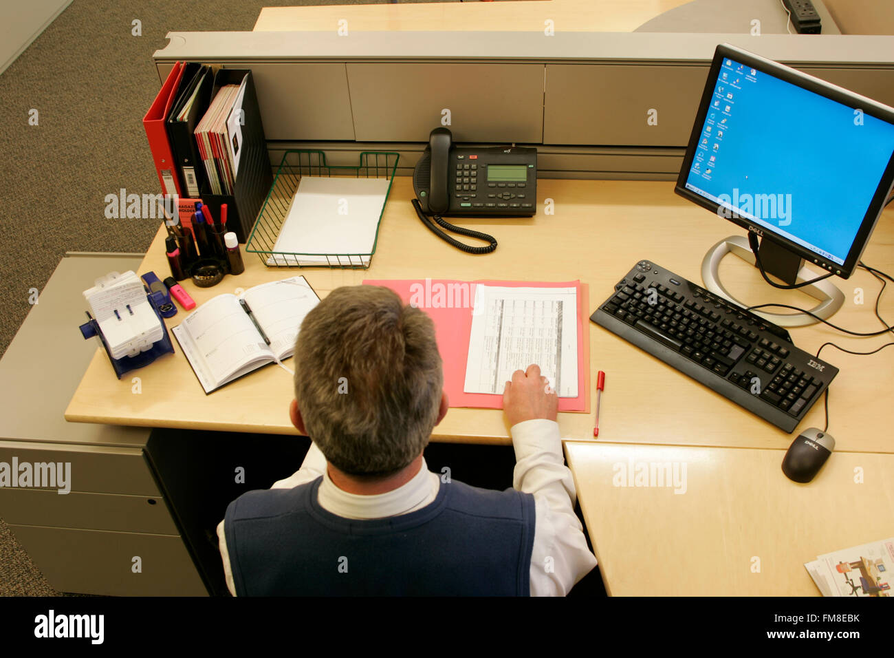 Man sitting at desk with computer, telephone and selection of office ...