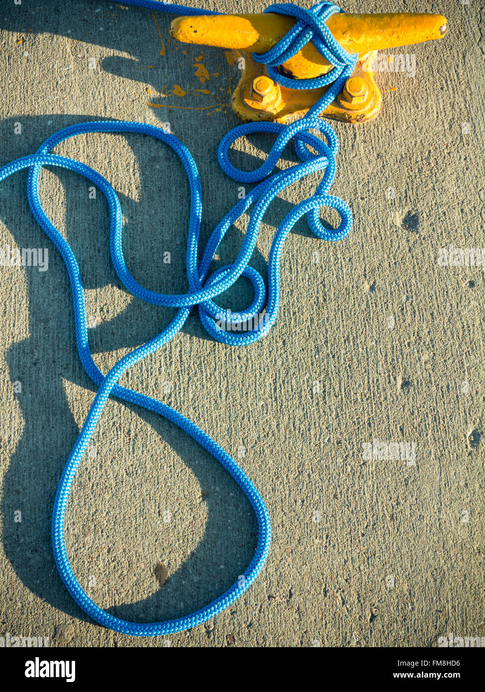 Yellow mooring bollard with blue rope in marina closeup Stock Photo - Alamy