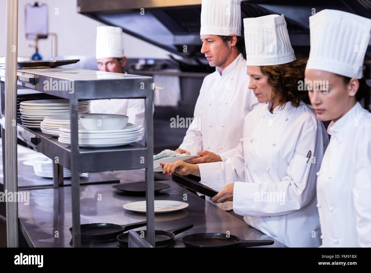 Team of chefs arranging plates on the order station Stock Photo - Alamy