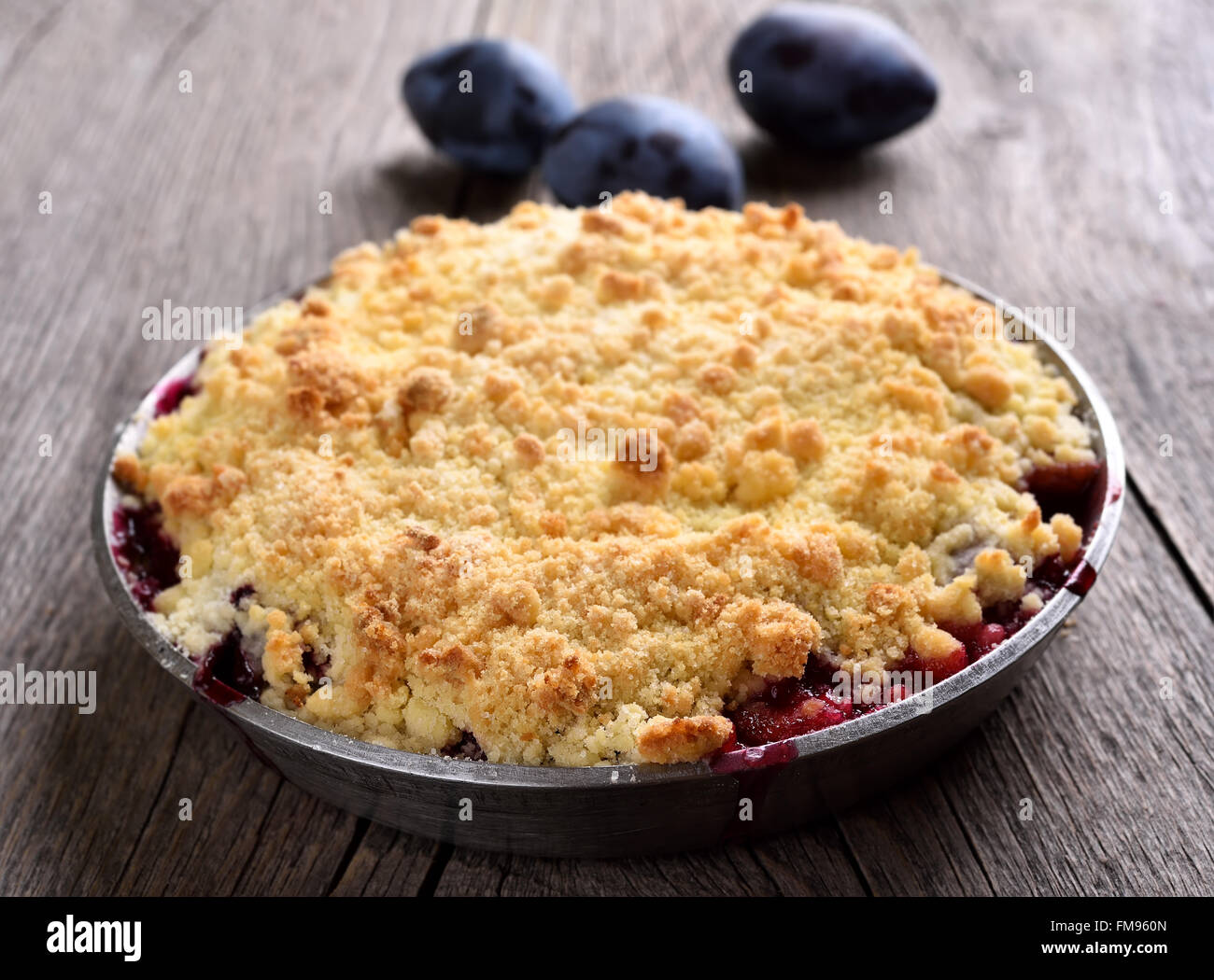 Plum crumb pie in pan on wooden background Stock Photo - Alamy